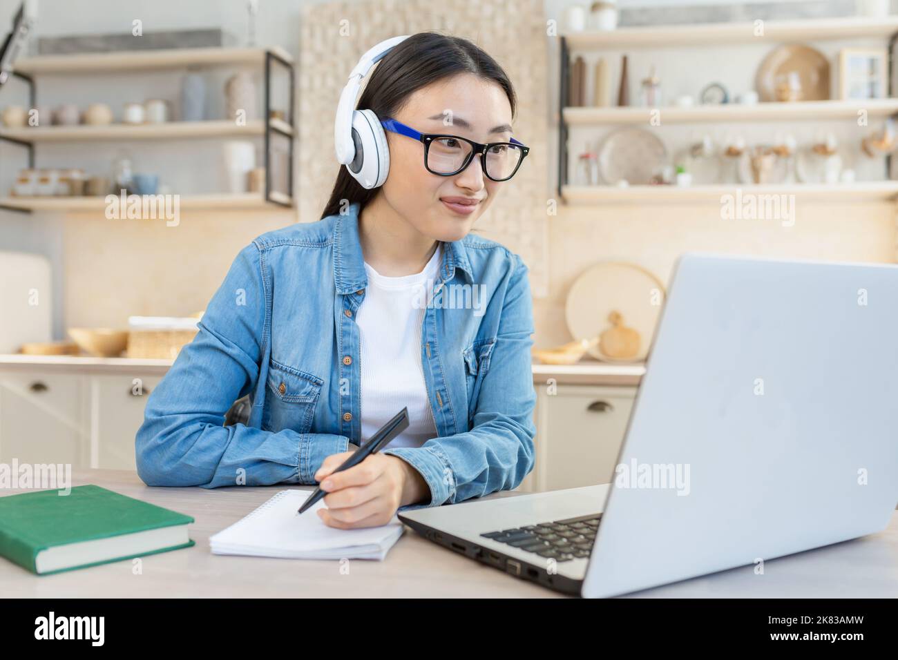 Online training. Young beautiful Asian girl sitting at the table at ...