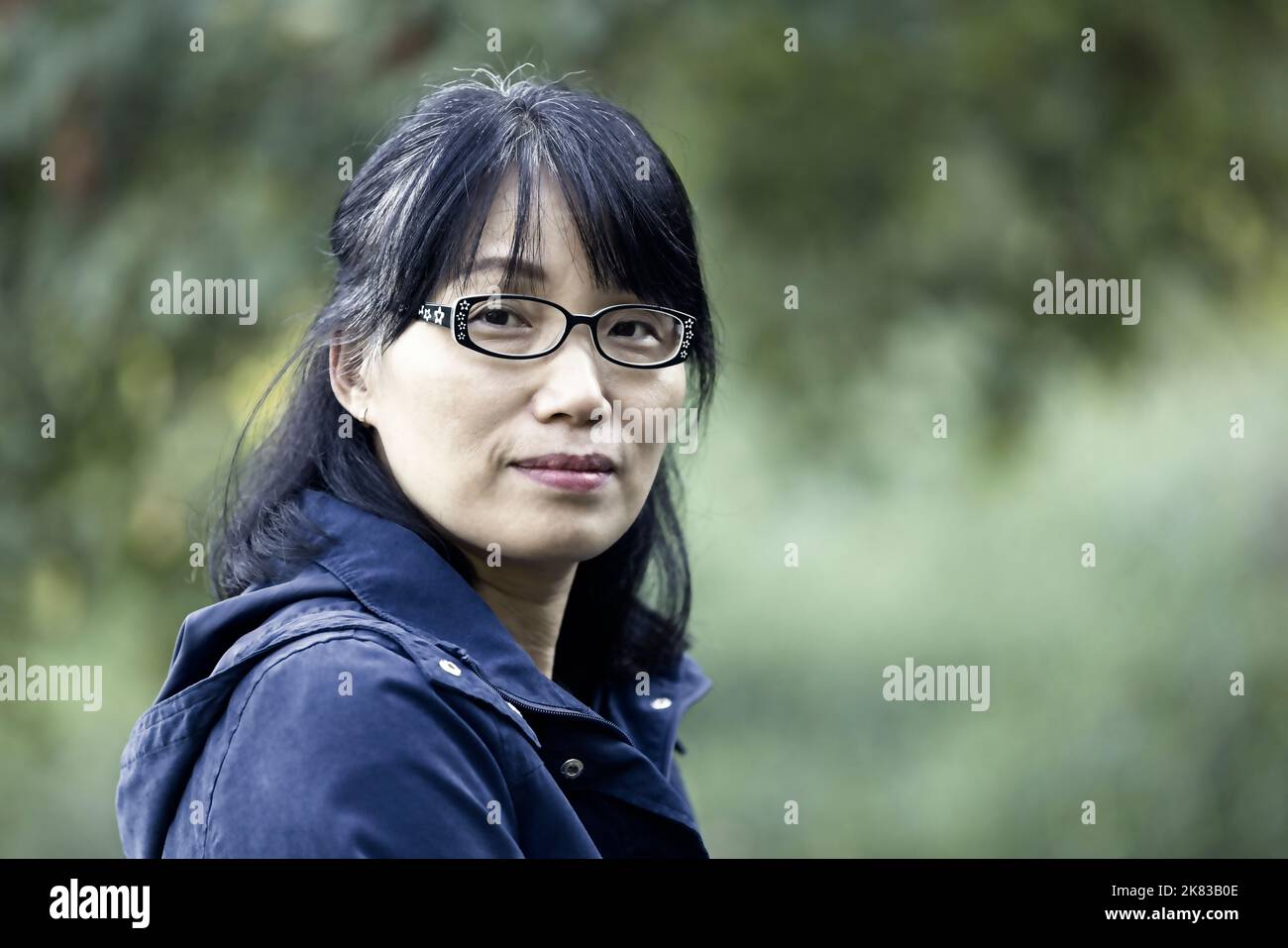 A pretty middle age Korean woman with a pleasant smile in a park in ...