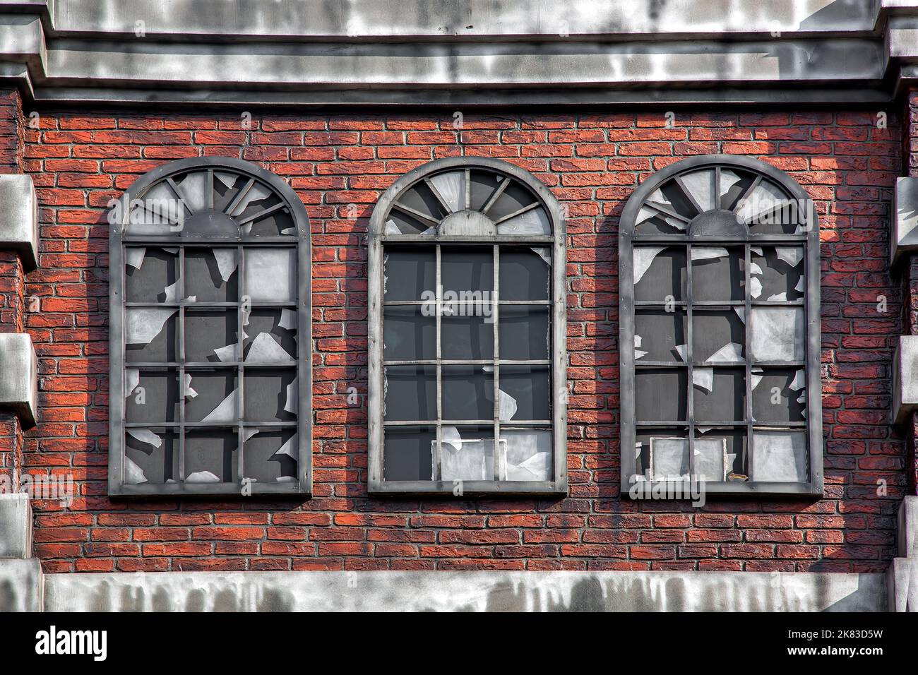 brick facade of an abandoned building with broken windows, an old uninhabited house in a ...