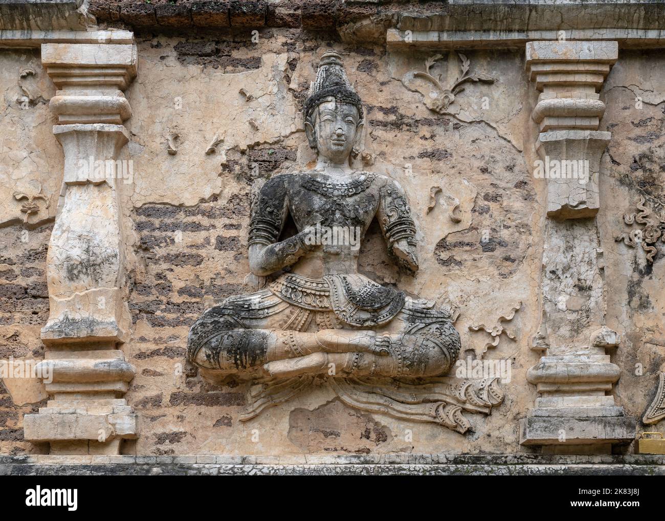 Ancient stucco life size carving of sitting deity on wall of Wat Chet ...