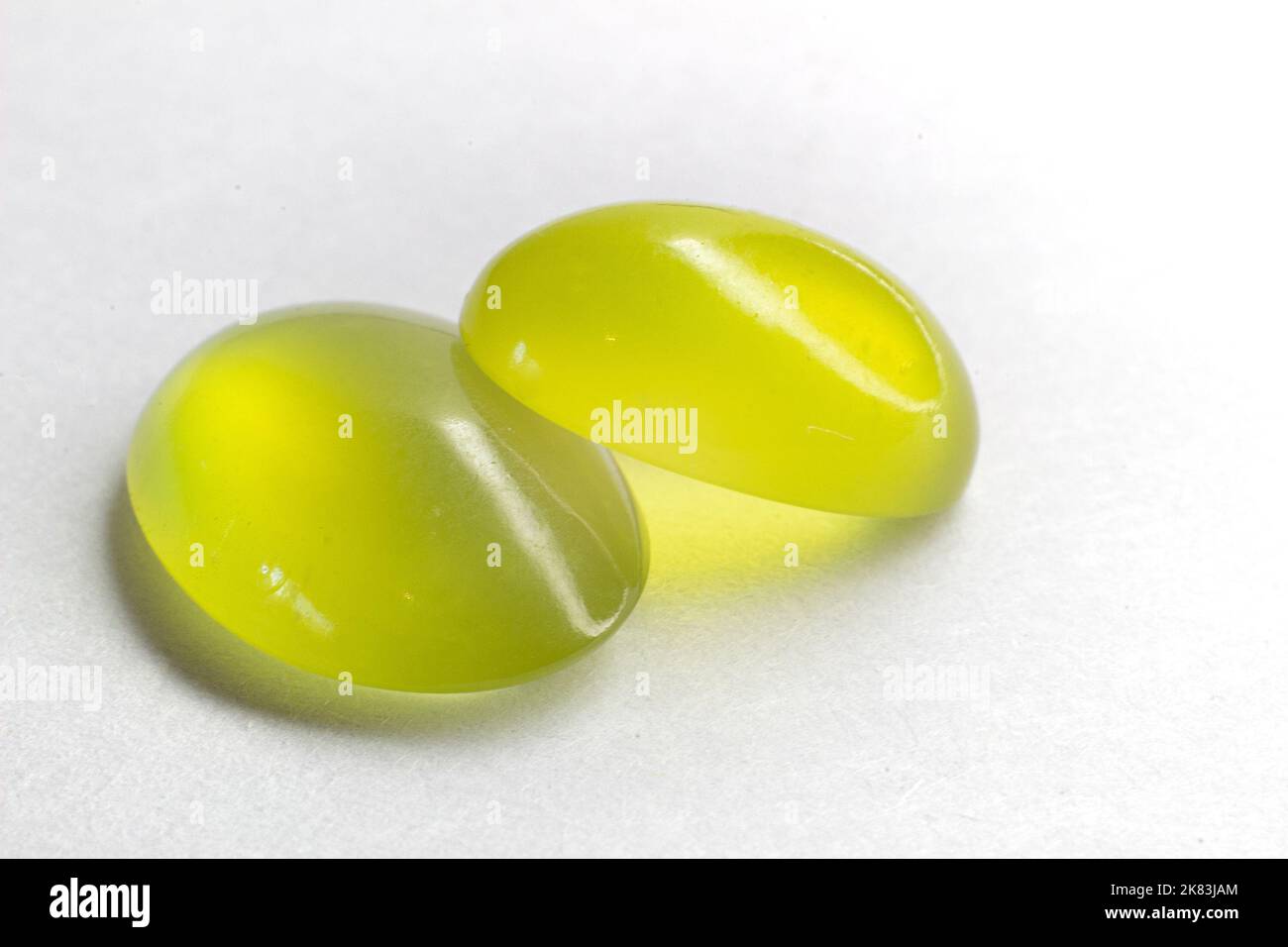 Two Peridots on top of each other on a white background. Olivine oval ...