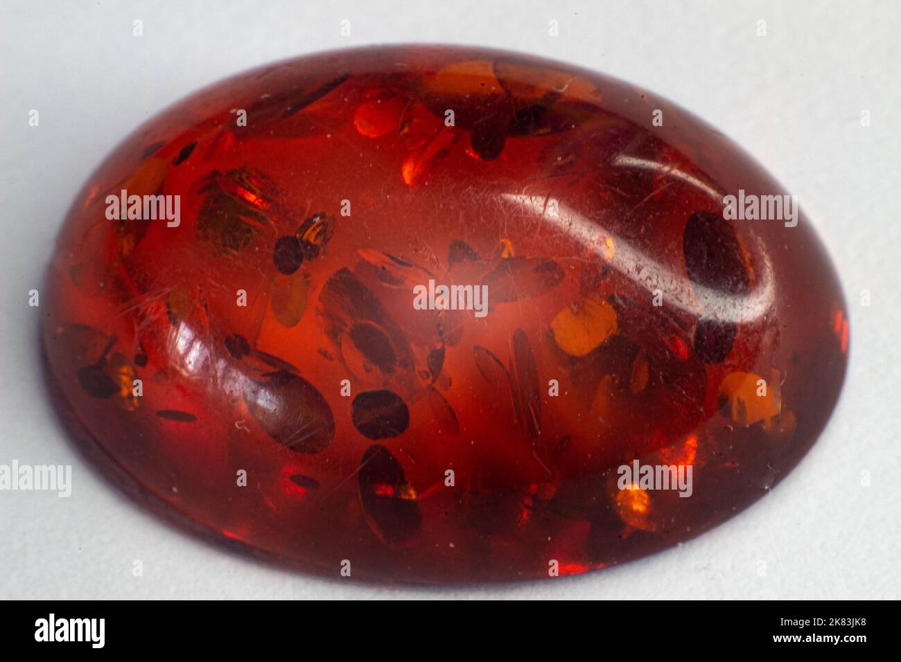 Macro heat treated deep orange amber cabochon with circular inclusions ...