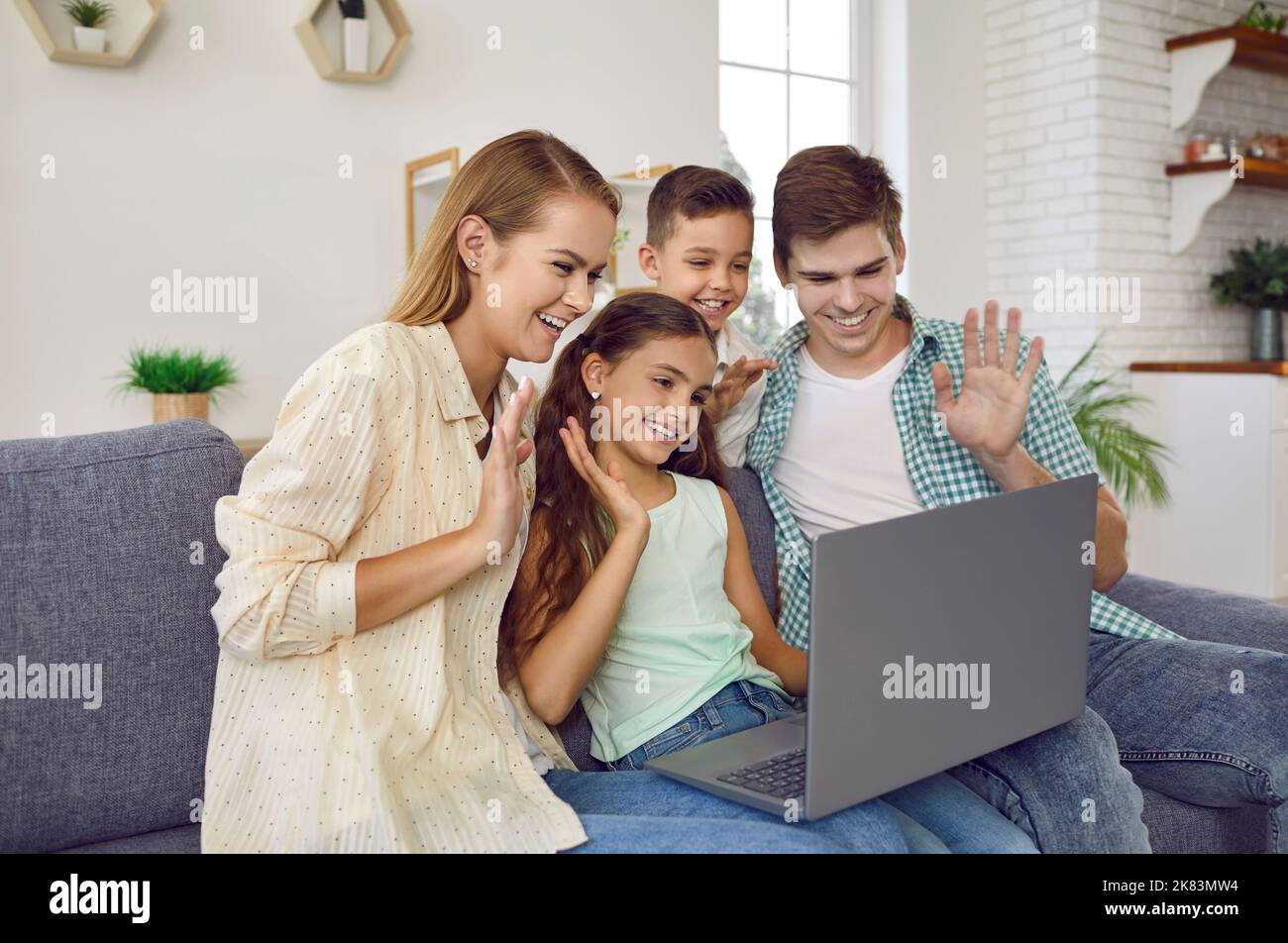 Happy family sitting on the sofa at home, making a video call and ...