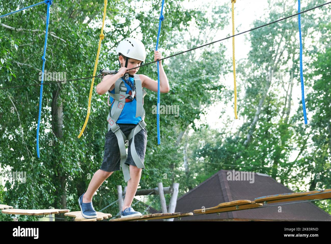 Child boy having summer fun at adventure park on the zip line. Balance ...