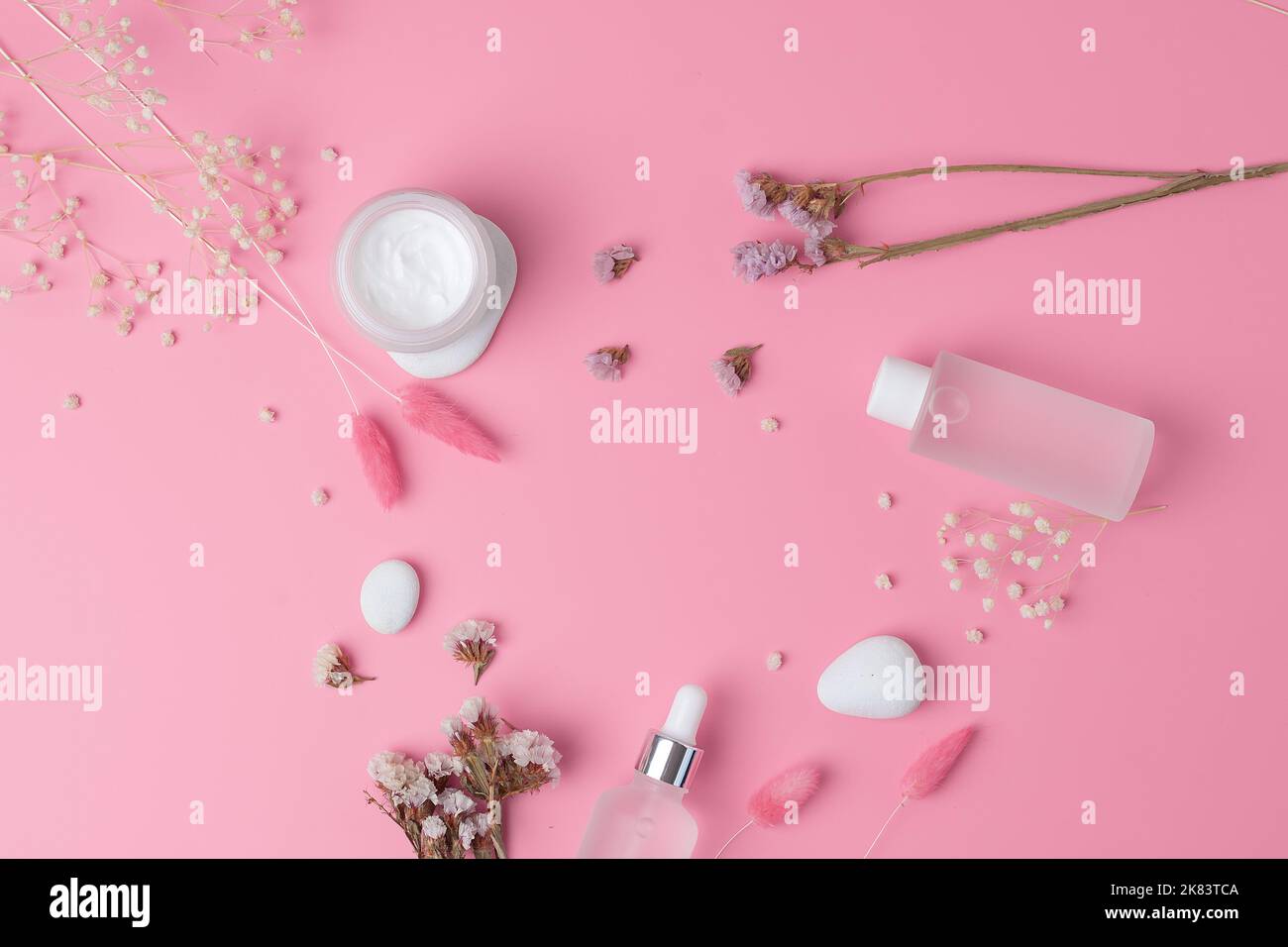 Cosmetic skin care products with flowers on pink background. Flat lay ...