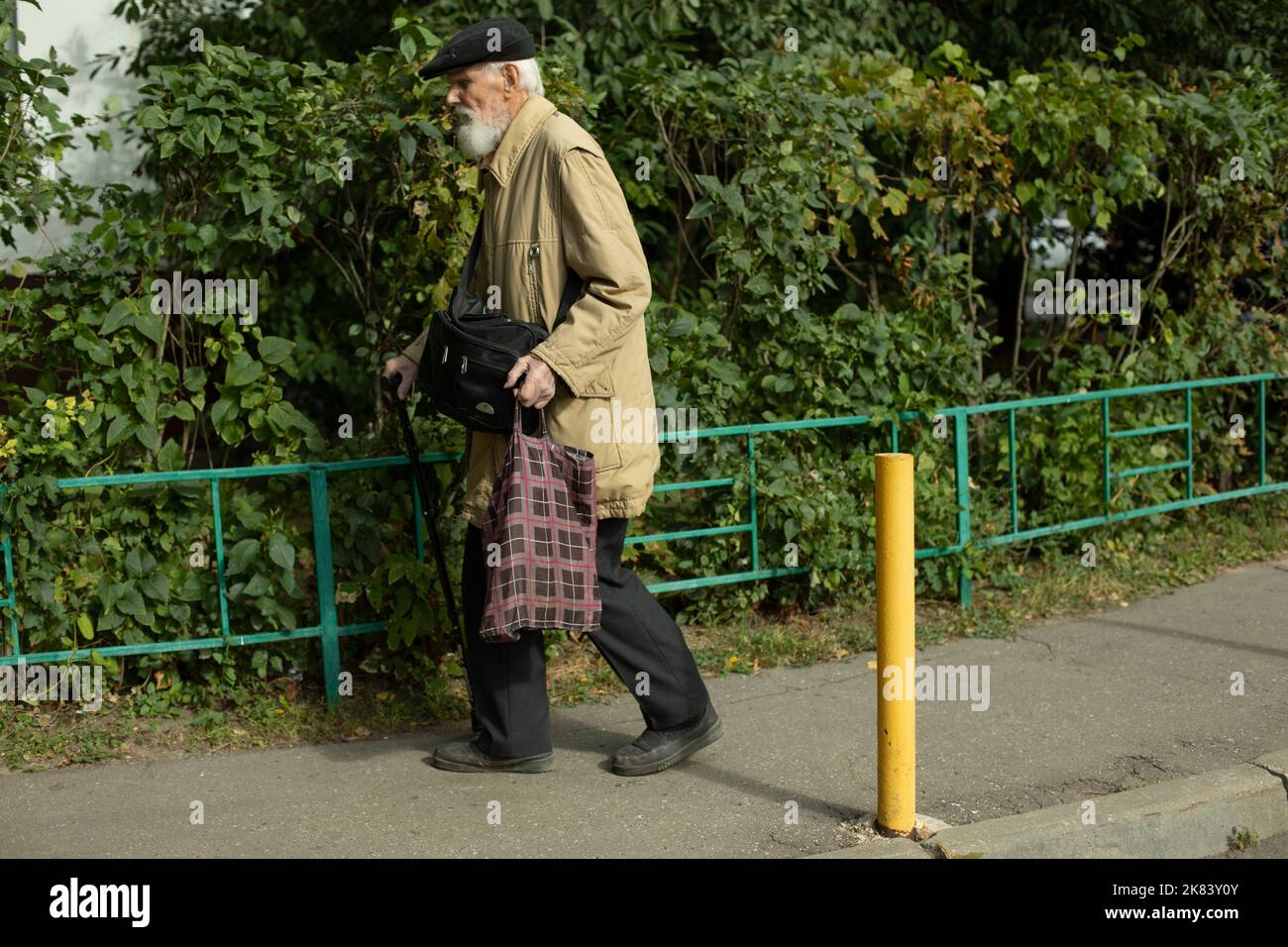 Old man is walking down street. Pensioner on track. Old man in yard ...