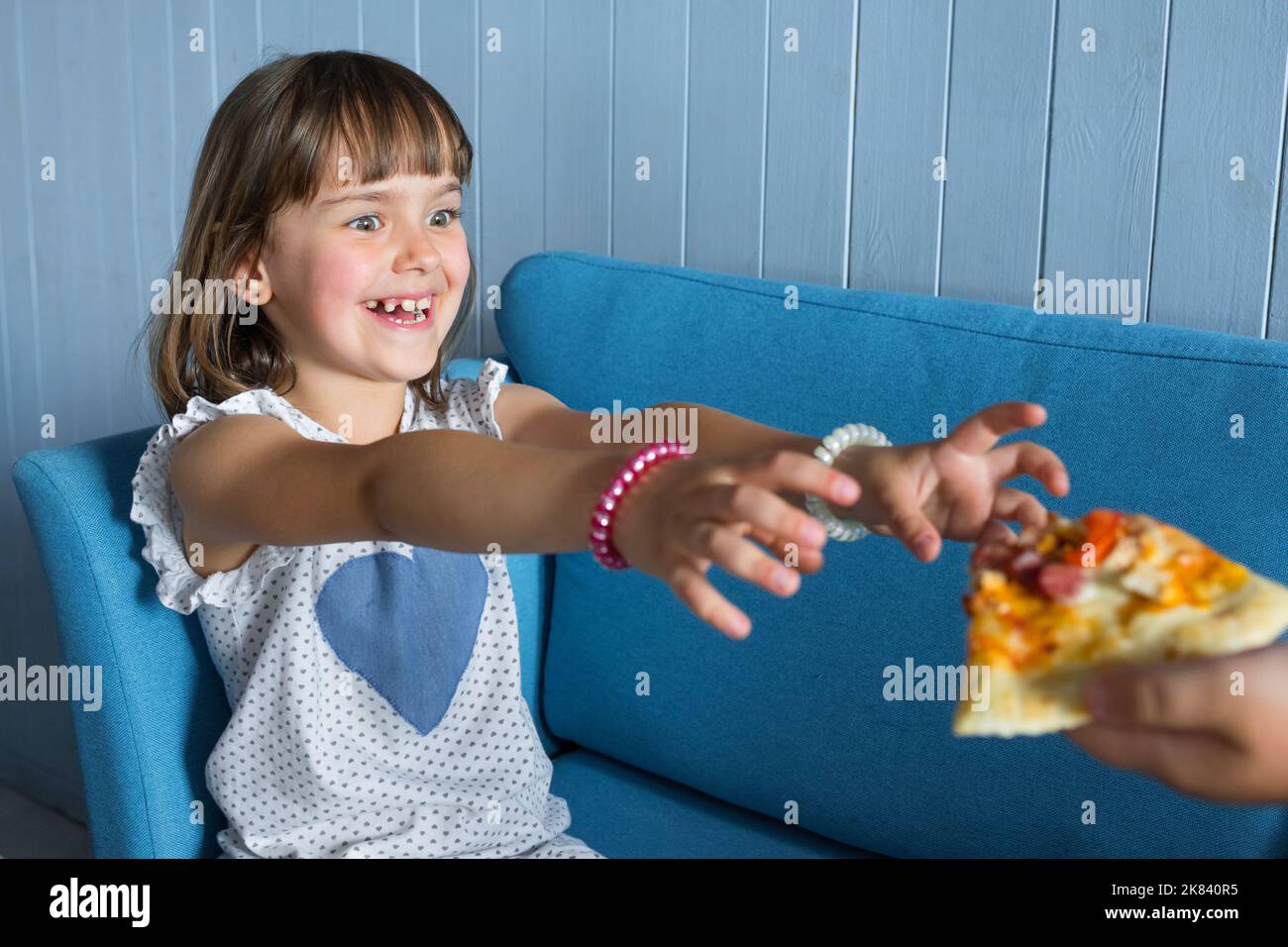 Happy little girl reaching out for pizza Stock Photo - Alamy
