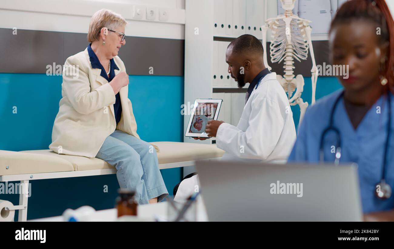 Cardiology medic showing cardiogram diagnosis on digital tablet to sick ...