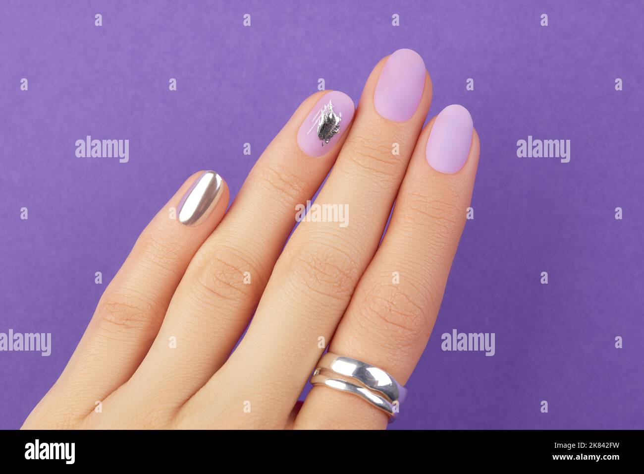 Close up womans hand with matte lavender nail design on purple ...
