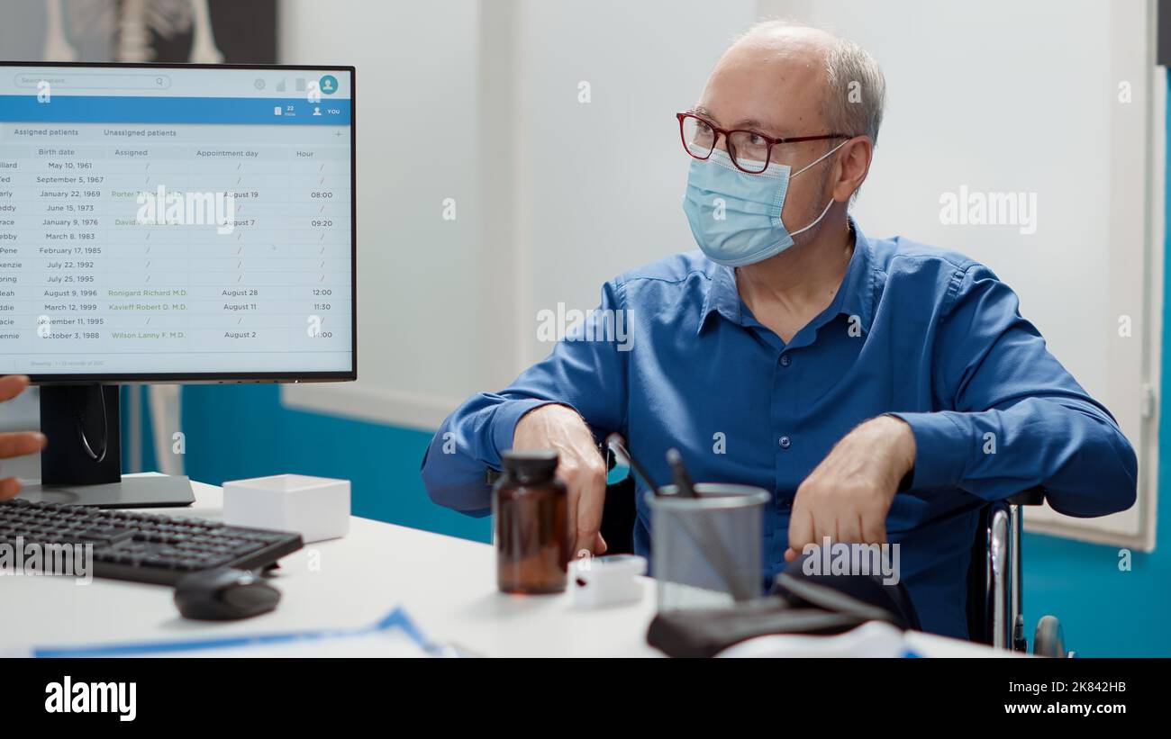 Elderly patient with face mask in wheelchair attending checkup visit ...