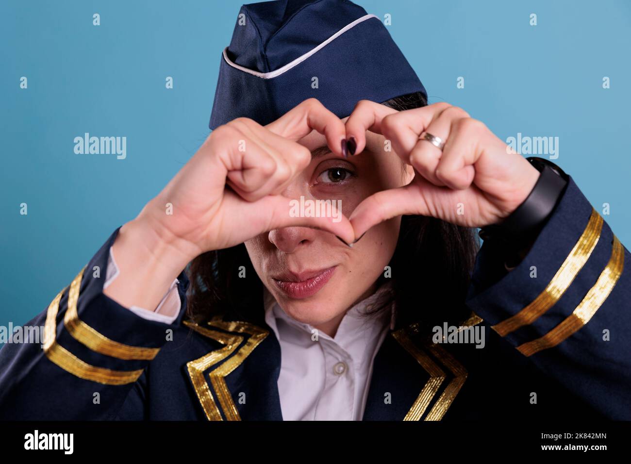 Smiling airliner stewardess showing heart shaped love symbol with ...