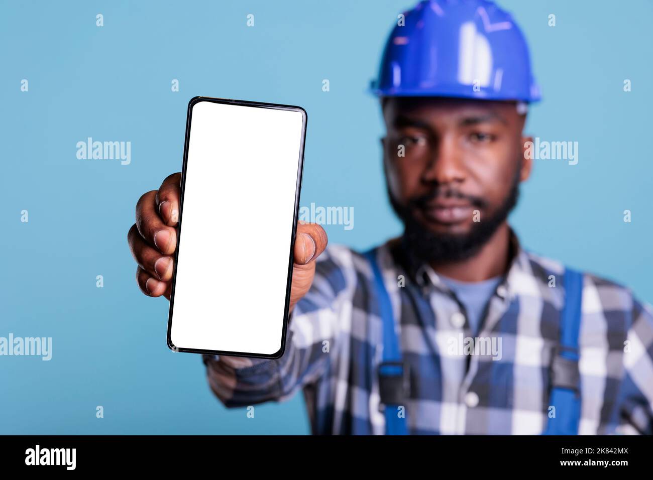 Serious construction worker showing modern phone with blank white ...