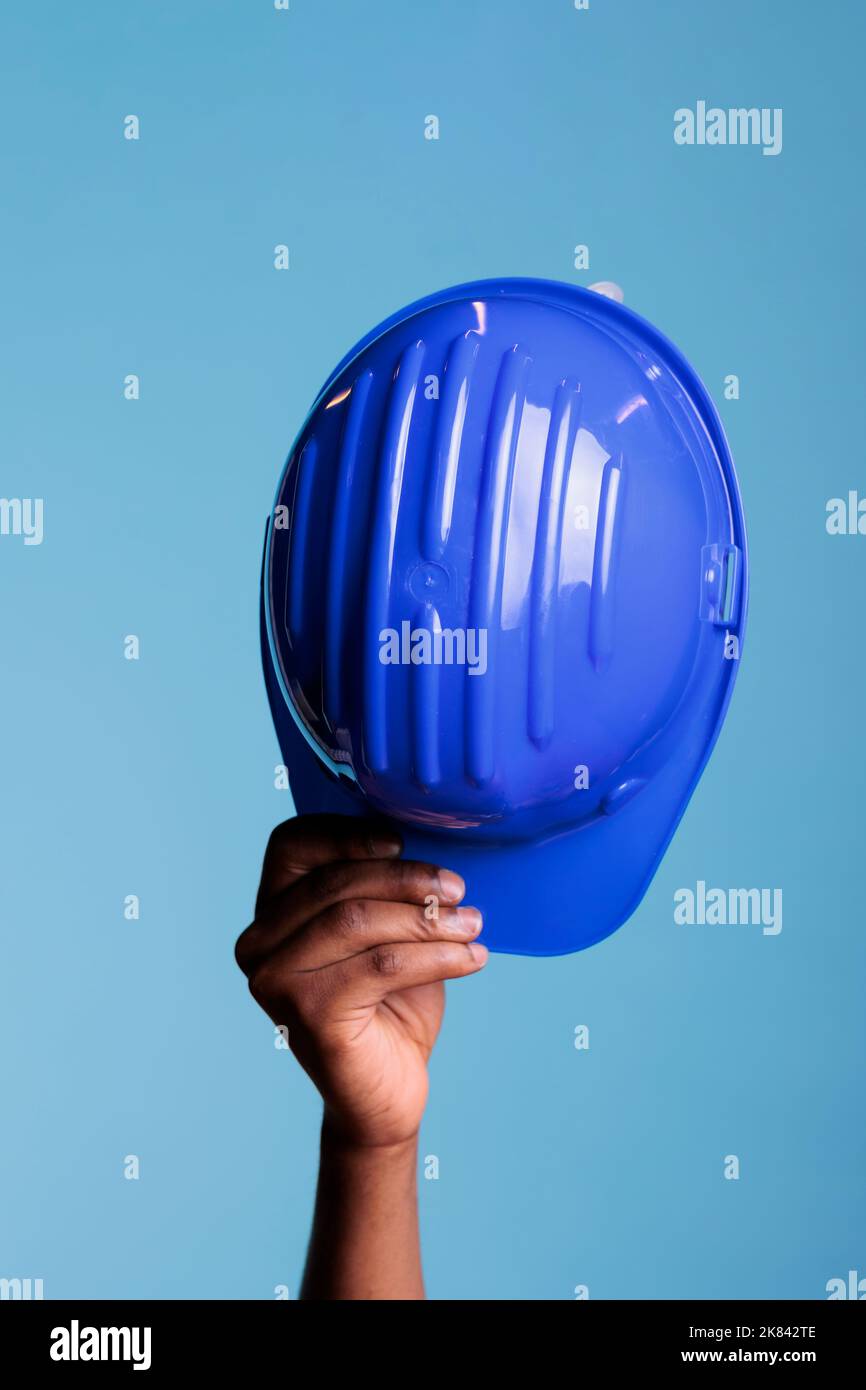 Construction worker holding a protective helmet in a studio shot on ...