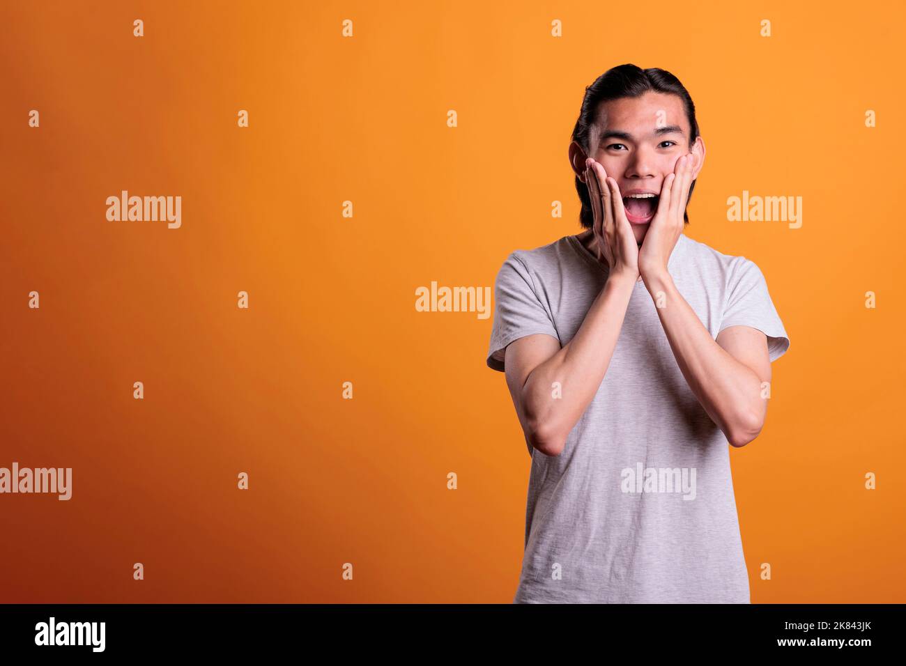 Shocked young man with hands on cheecks and open mouth, news hearing ...