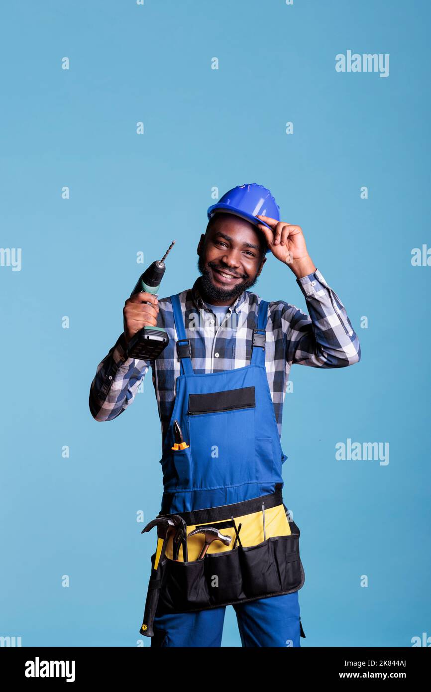 Happy african american construction worker adjusting hard hat holding ...