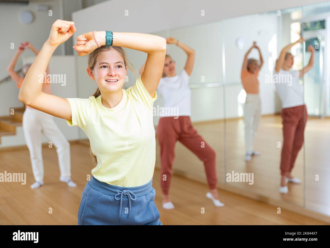 Teen girl with family doing aerobics exercises with group of people in ...