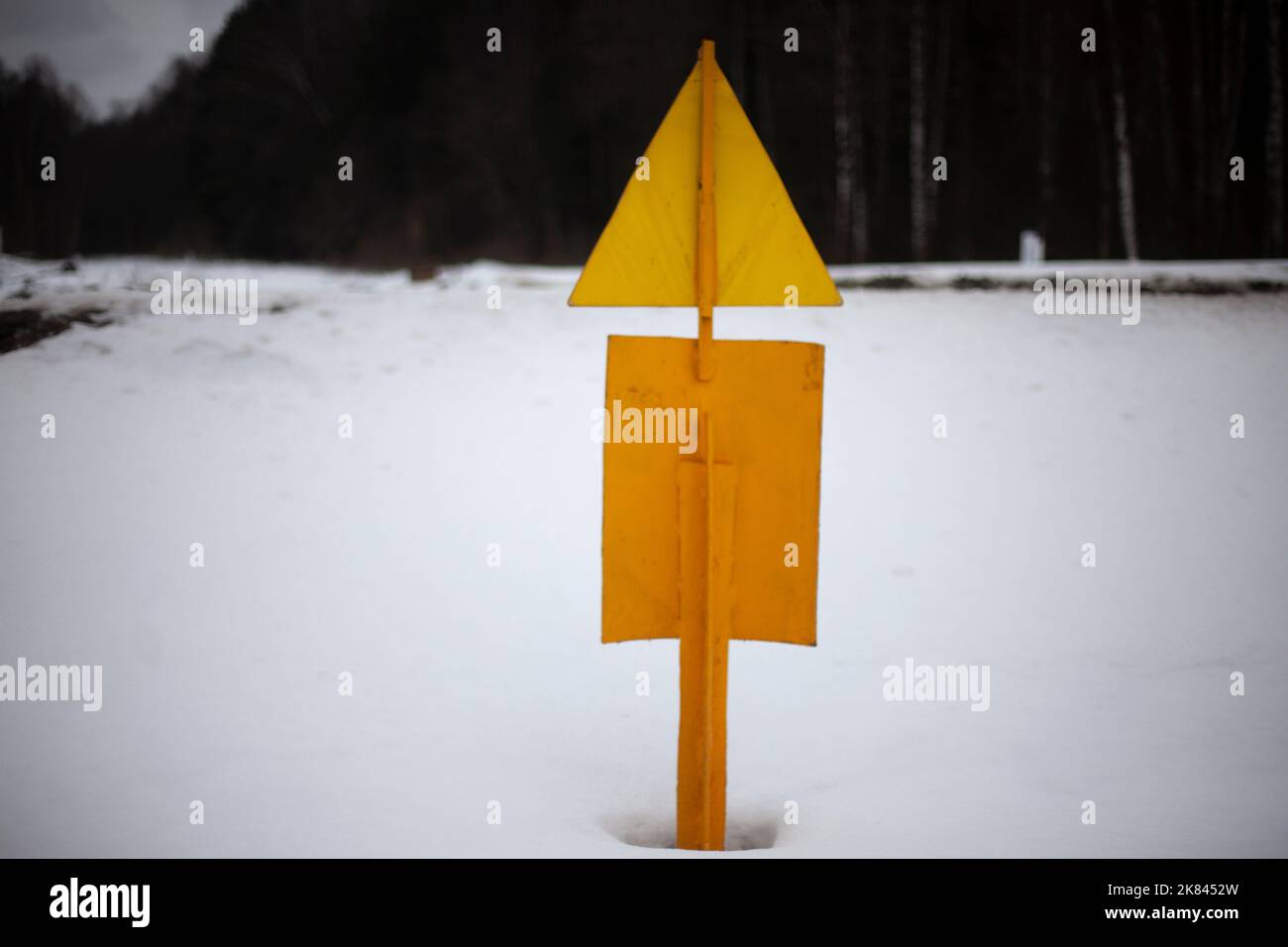 Yellow sign in snow. Steel pole in ground. Warning signal. Pipeline ...