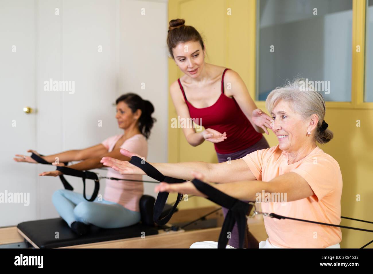 Senior woman exercising on pilates reformer with young trainer Stock ...