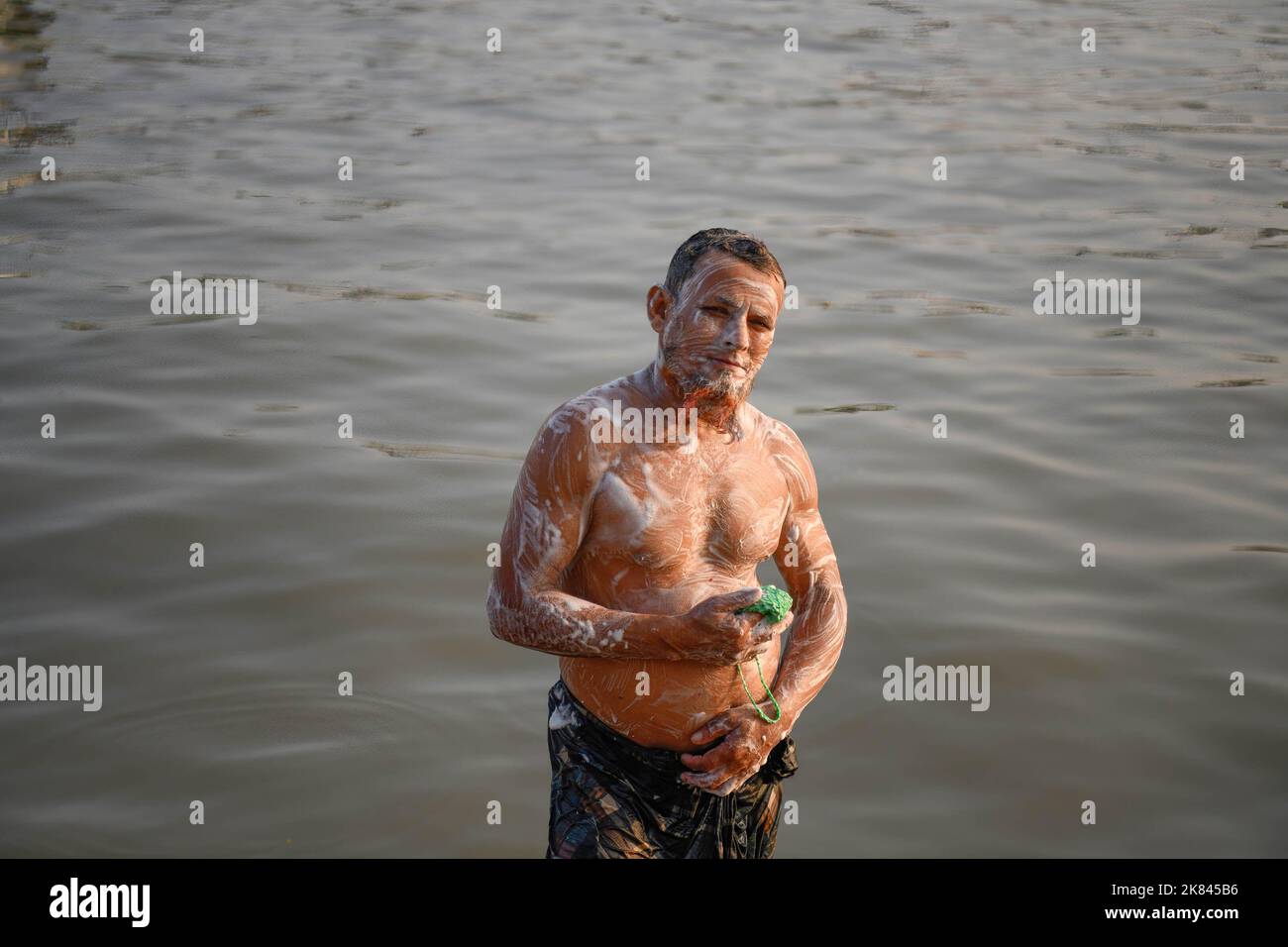 Mohammad Ismail poses for a portrait while taking a bath on the bank of ...
