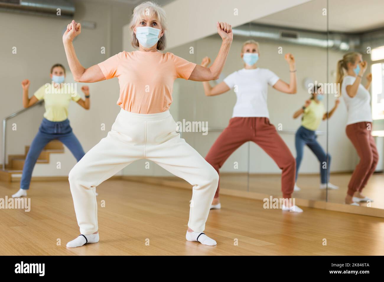 Family in protective masks are engaged in sports dancing in gym Stock ...