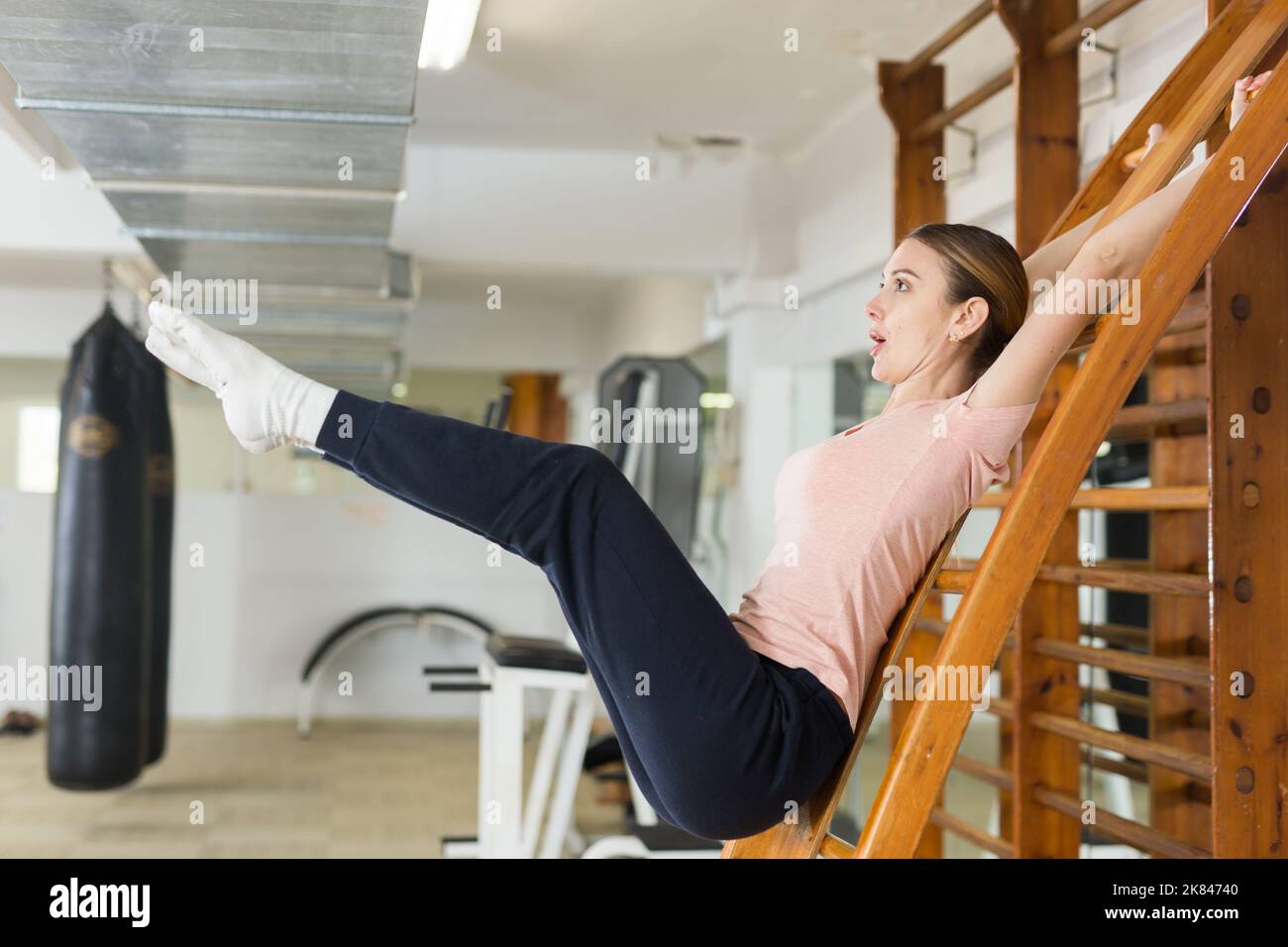 Young woman performing leg raises on wall bars in gym Stock Photo - Alamy