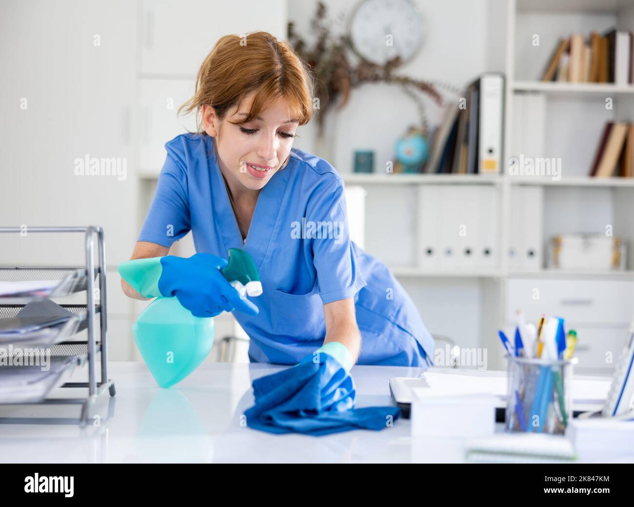 Positive woman cleaner polishing table in office Stock Photo - Alamy