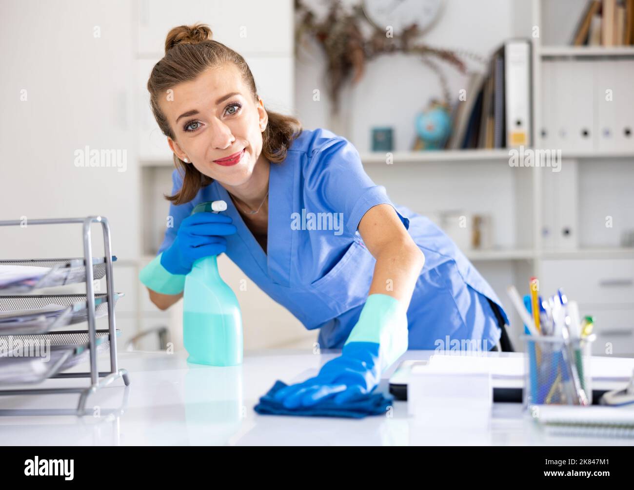 Positive woman cleaner polishing table in office Stock Photo - Alamy