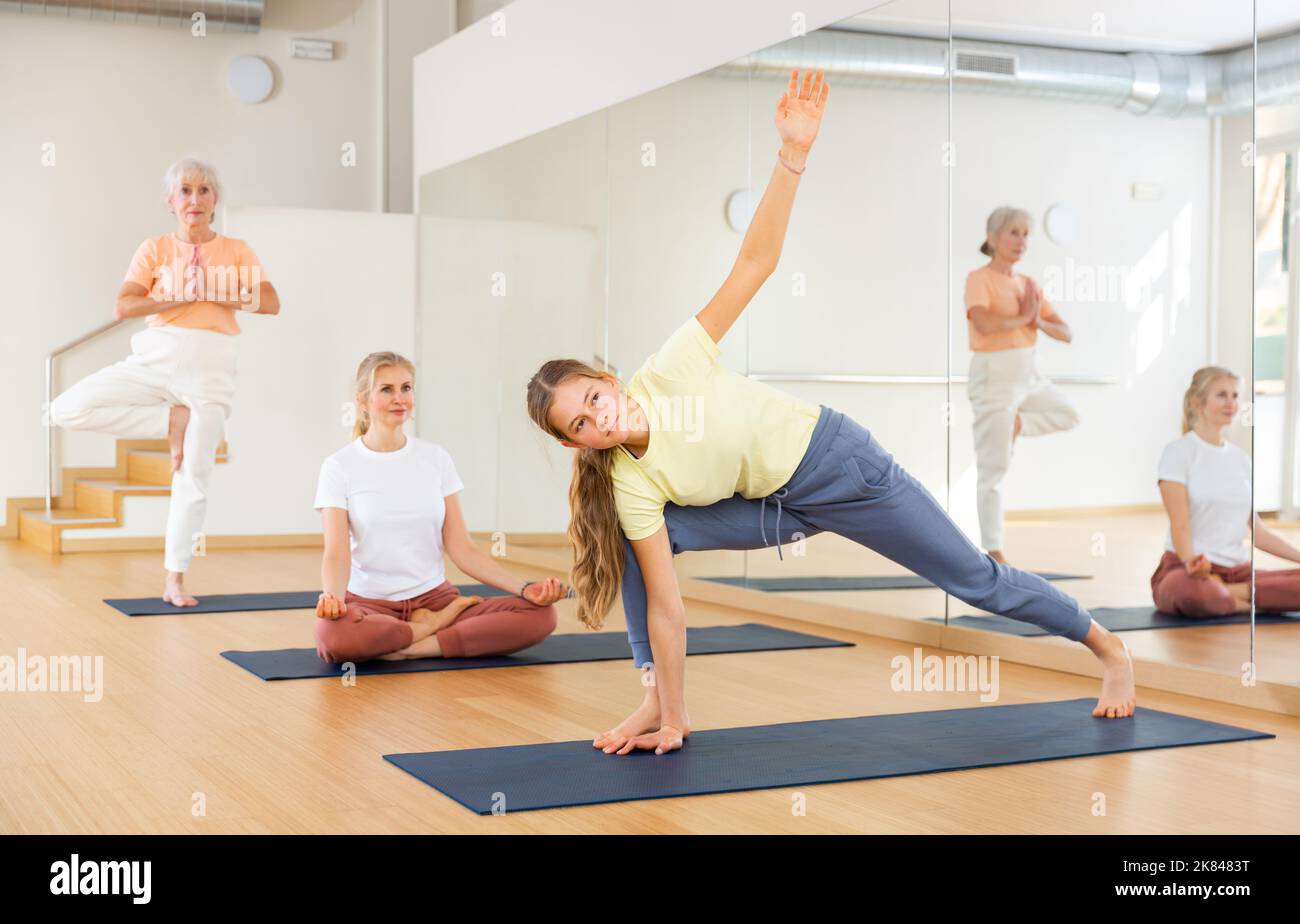 Women exercising yoga poses in fitness gym. Extended triangle pose ...