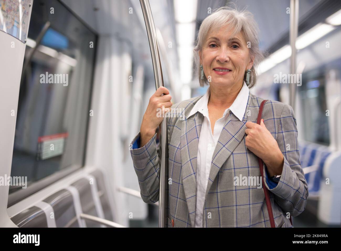 Senior lady standing in metro train Stock Photo - Alamy