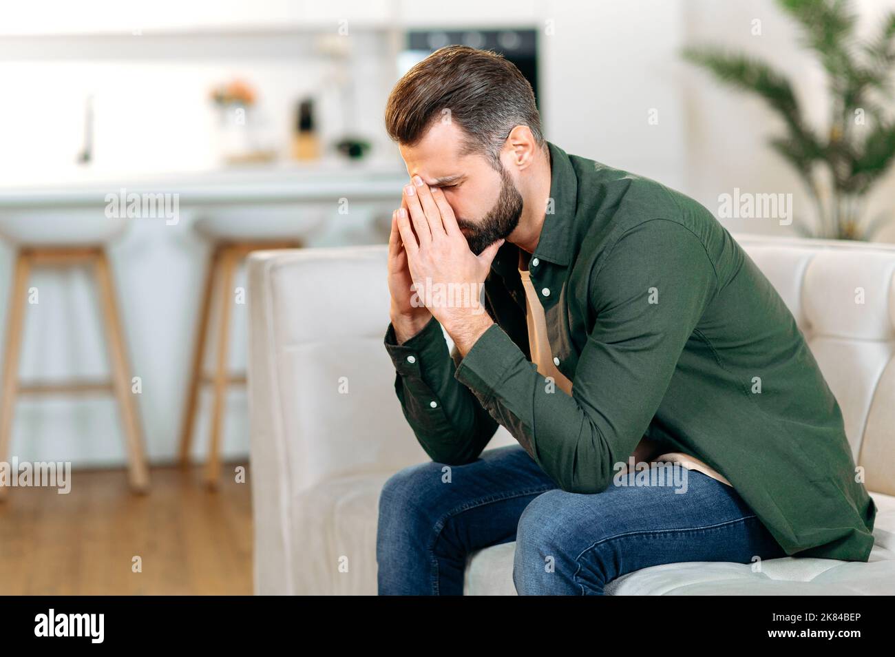 Unhappy frustrated caucasian man, sit on sofa in living room with his ...