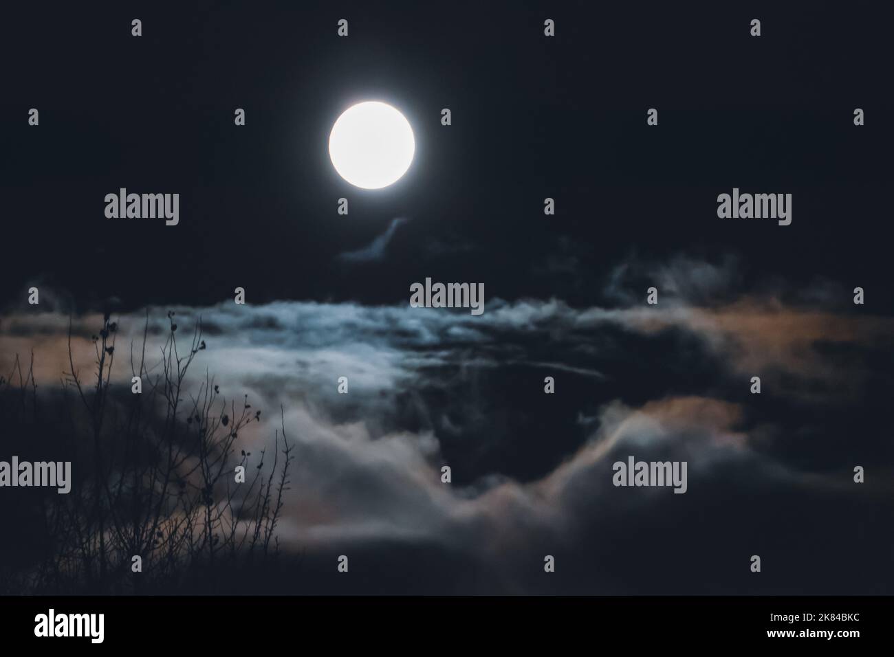 Full moon over clouds and fog in night sky, nebulous blurry landscape ...