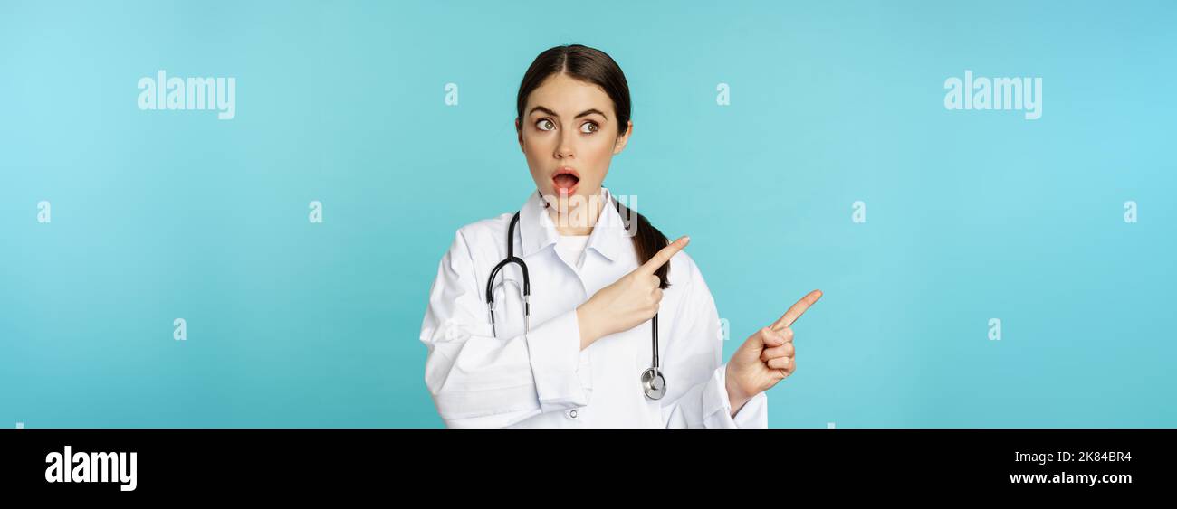 Surprised female doctor, physician with stethoscope, pointing and ...