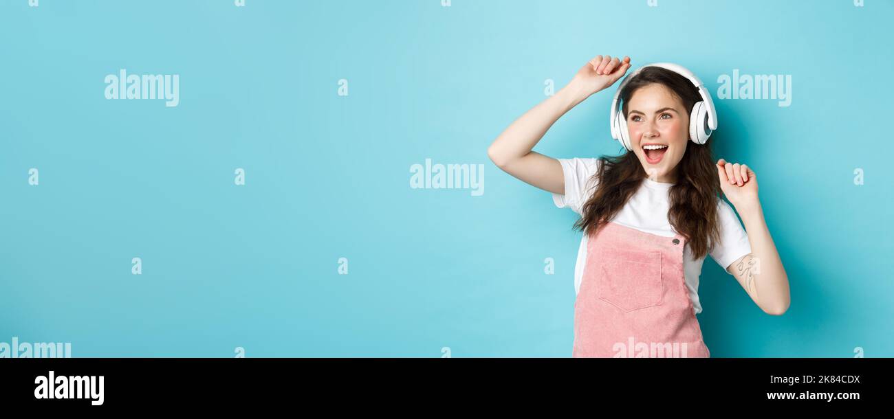 Image of cheerful young pretty girl dancing in headphones, listening ...