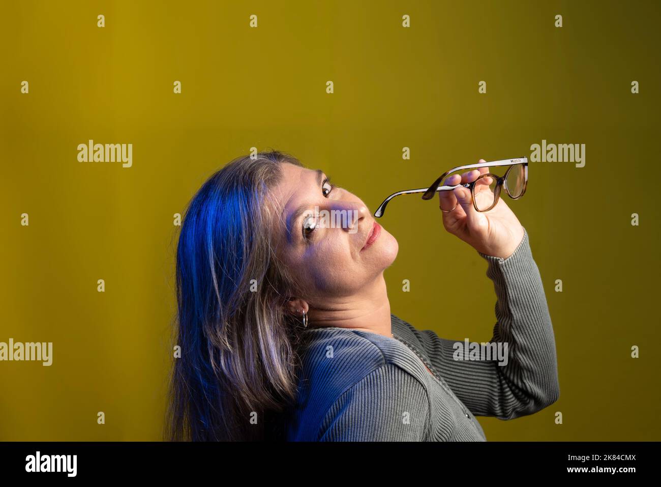 Portrait of model wearing eyeglasses against yellow background. She ...