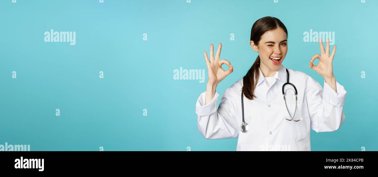 Smiling woman doctor, professional medical worker, showing okay, ok ...