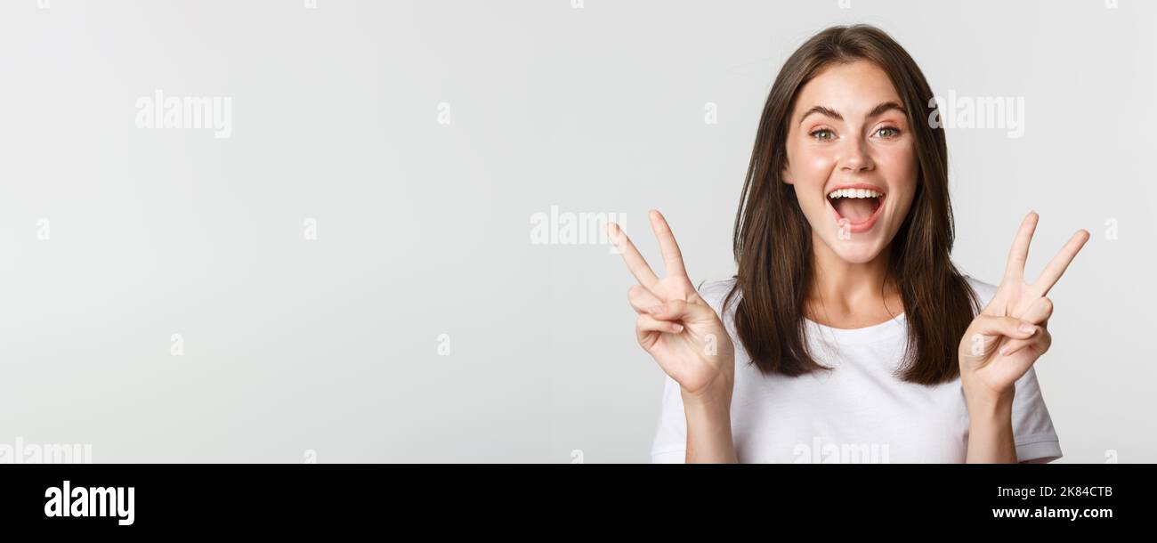 Portrait of beautiful and happy brunette girl smiling and showing peace ...