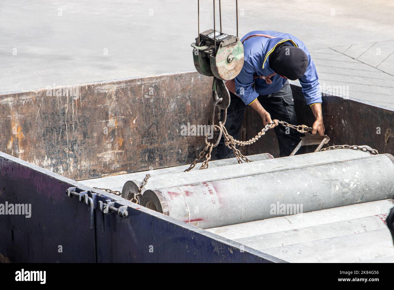 A worker attaches chains from a crane to concrete tubes on the load ...