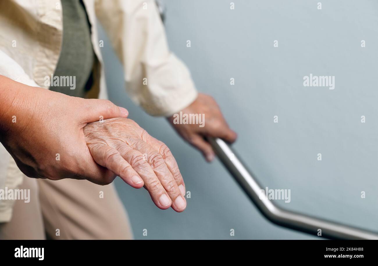 Elderly woman holding on handrail with caregiver Stock Photo - Alamy