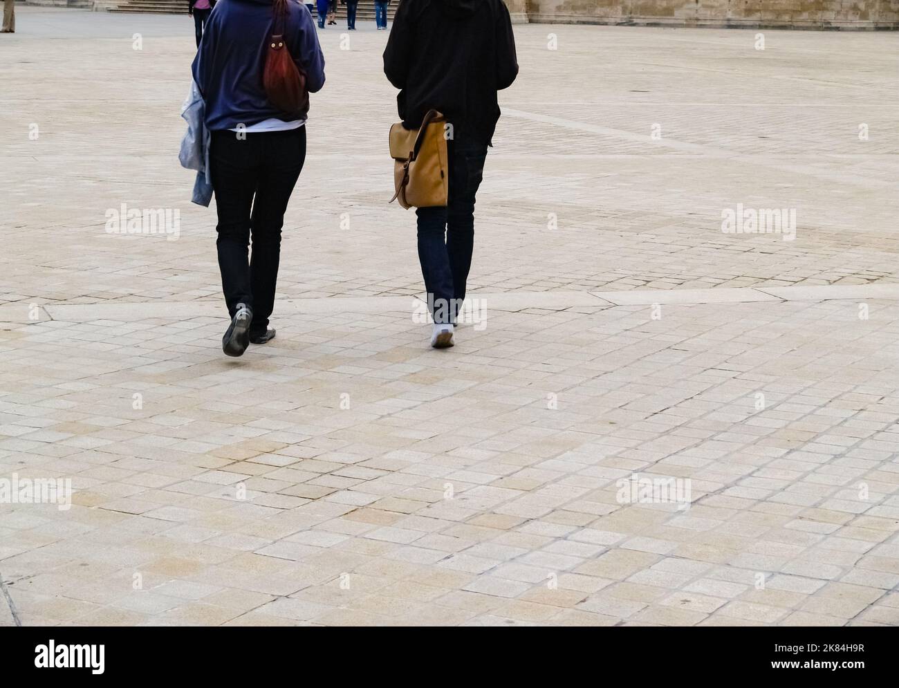 Back view two people dressed in black shoulders down, walking away ...