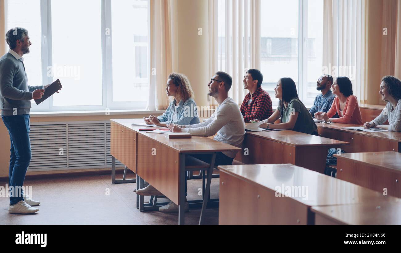Male professor in casual clothes is talking to group of students ...