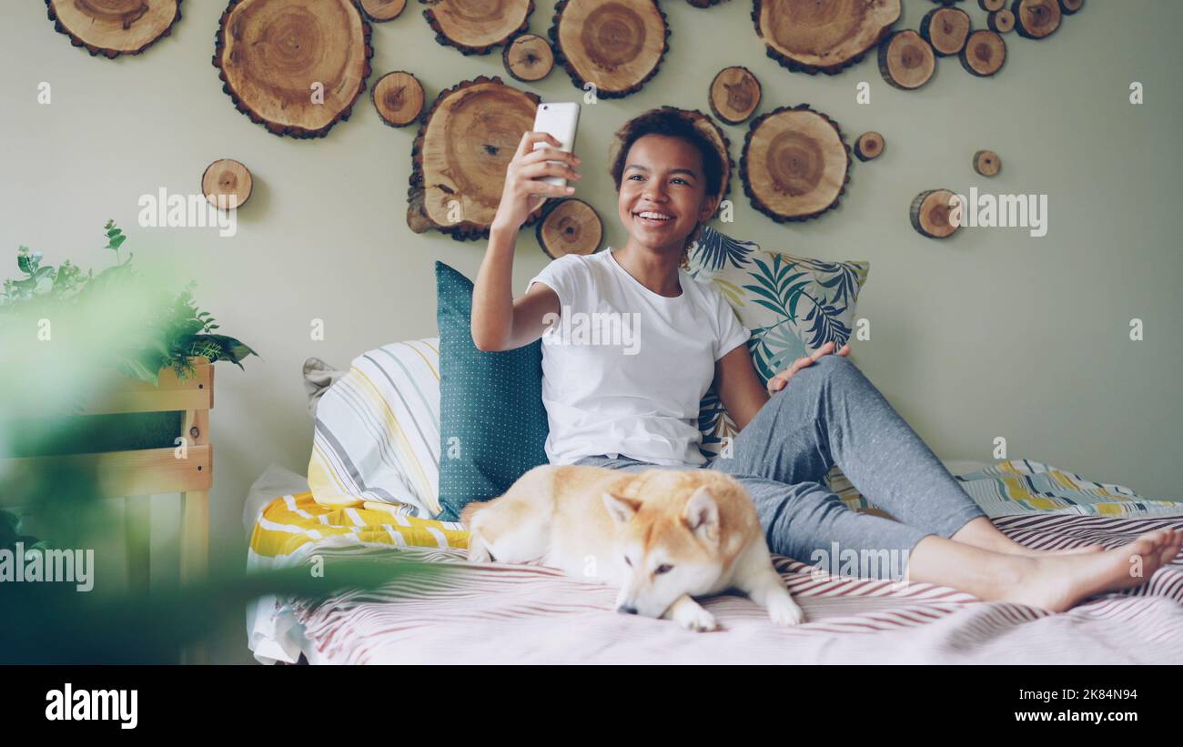 Happy African American teenager is making video call with smartphone ...