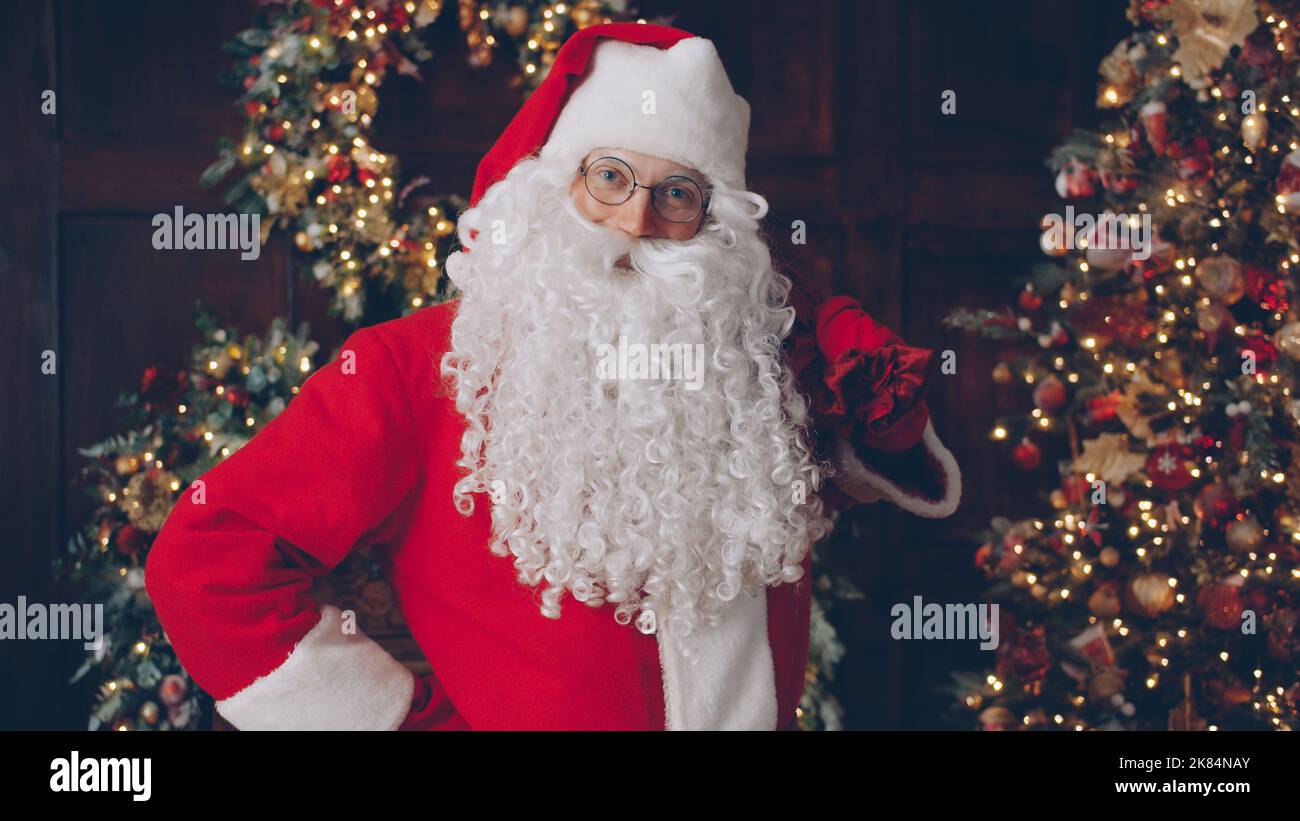 Portrait of merry Santa Clause holding bag with presents near Christmas ...