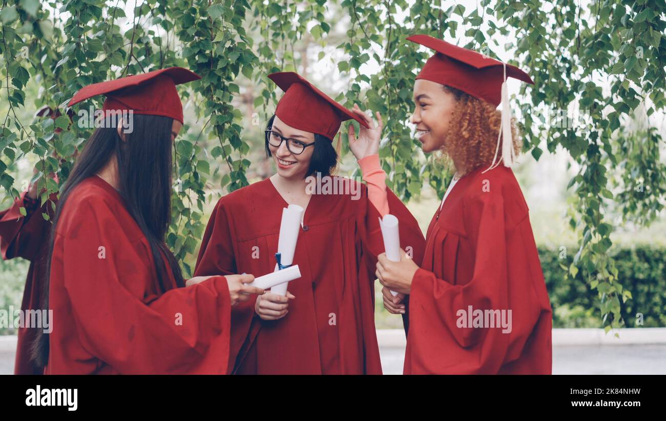Three pretty girls graduates are talking and holding diplomas on ...