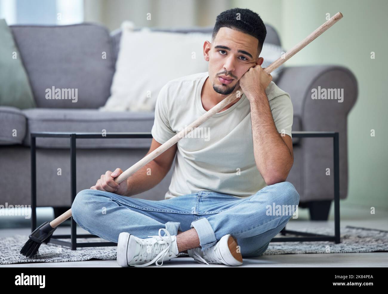 When do all the chores end. a young man sitting with a broom at home ...