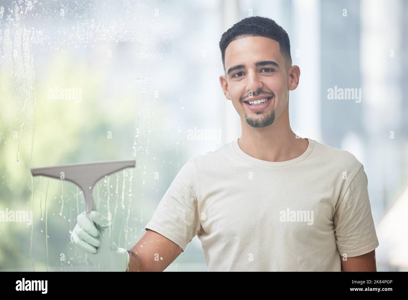 Clean windows make me happy. a young man cleaning a glass window at ...