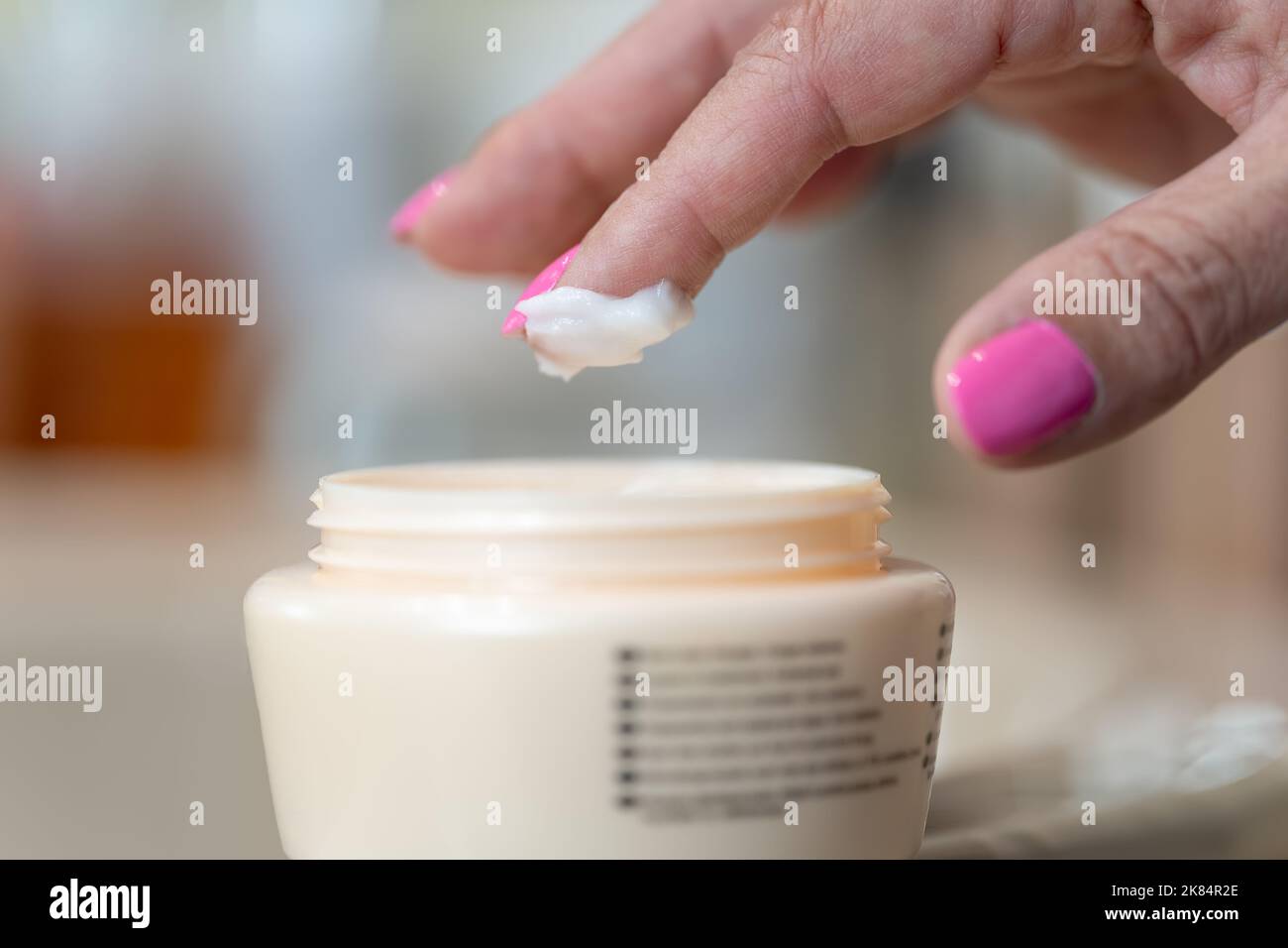 Senior woman's hand picking cream with her finger for personal skin ...