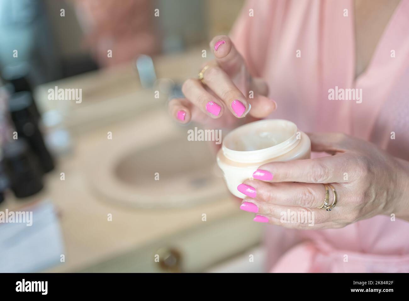 Senior woman's hand taking cream from a bottle for skin care and ...