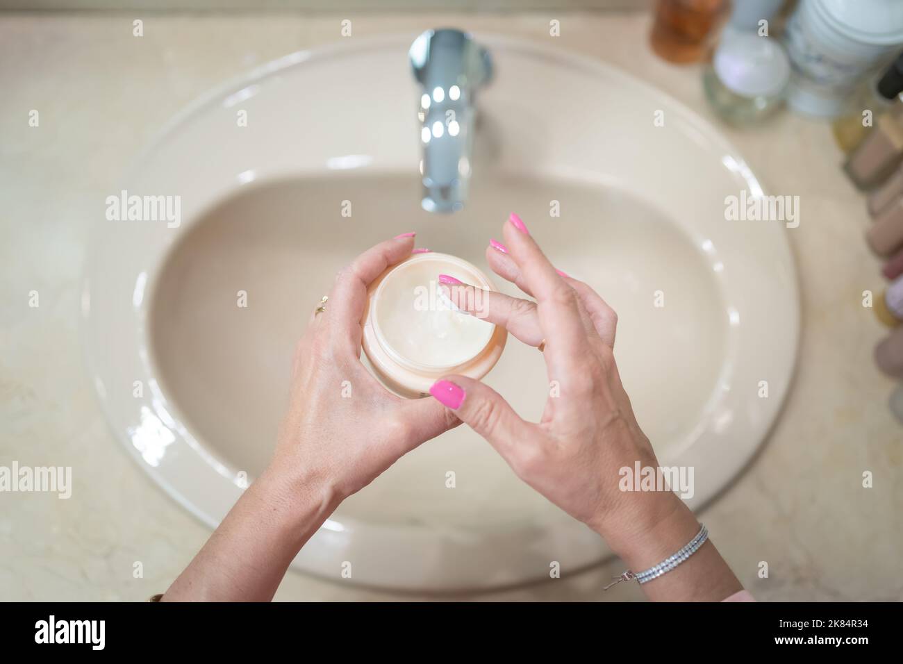 Senior woman's hand taking cream from a bottle for skin care and ...