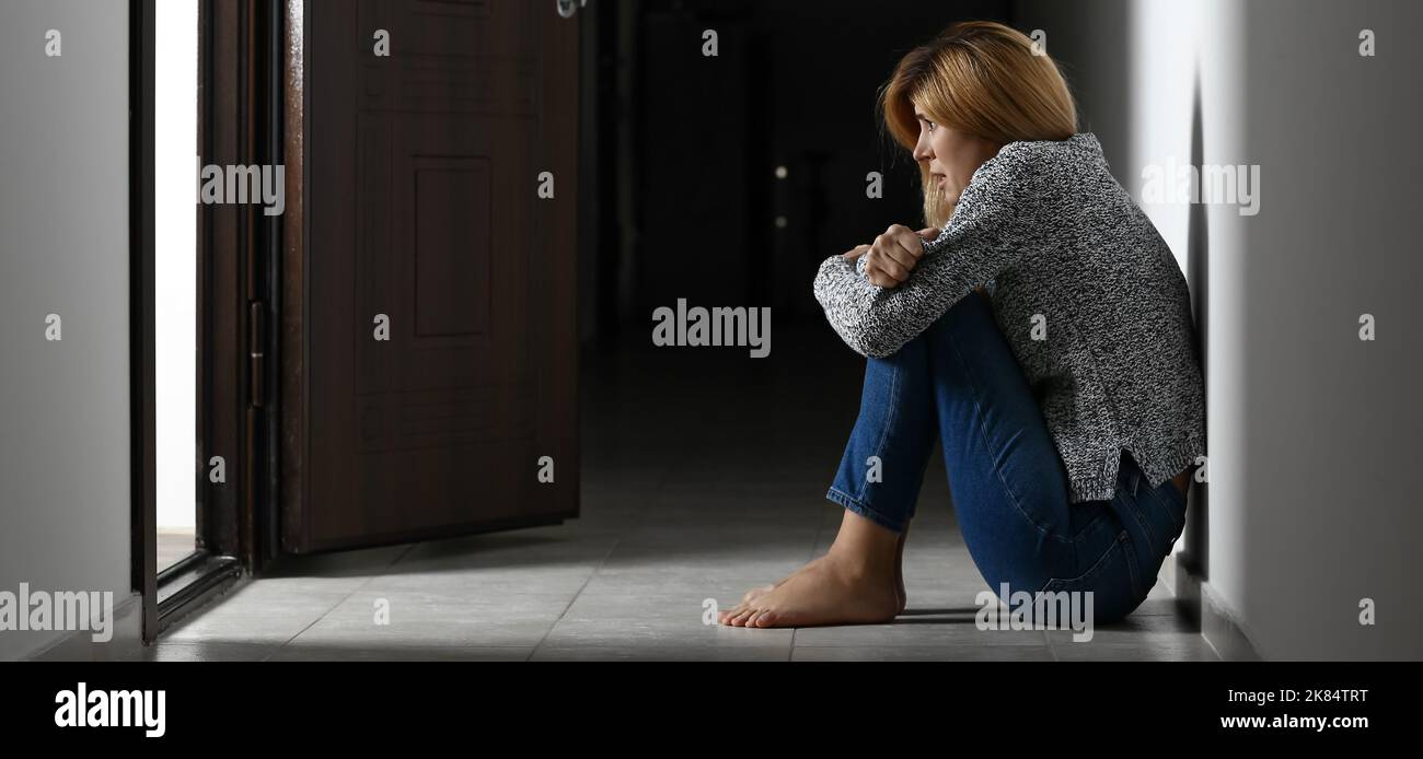 Scared woman sitting on floor in hallway. Panic attack Stock Photo - Alamy