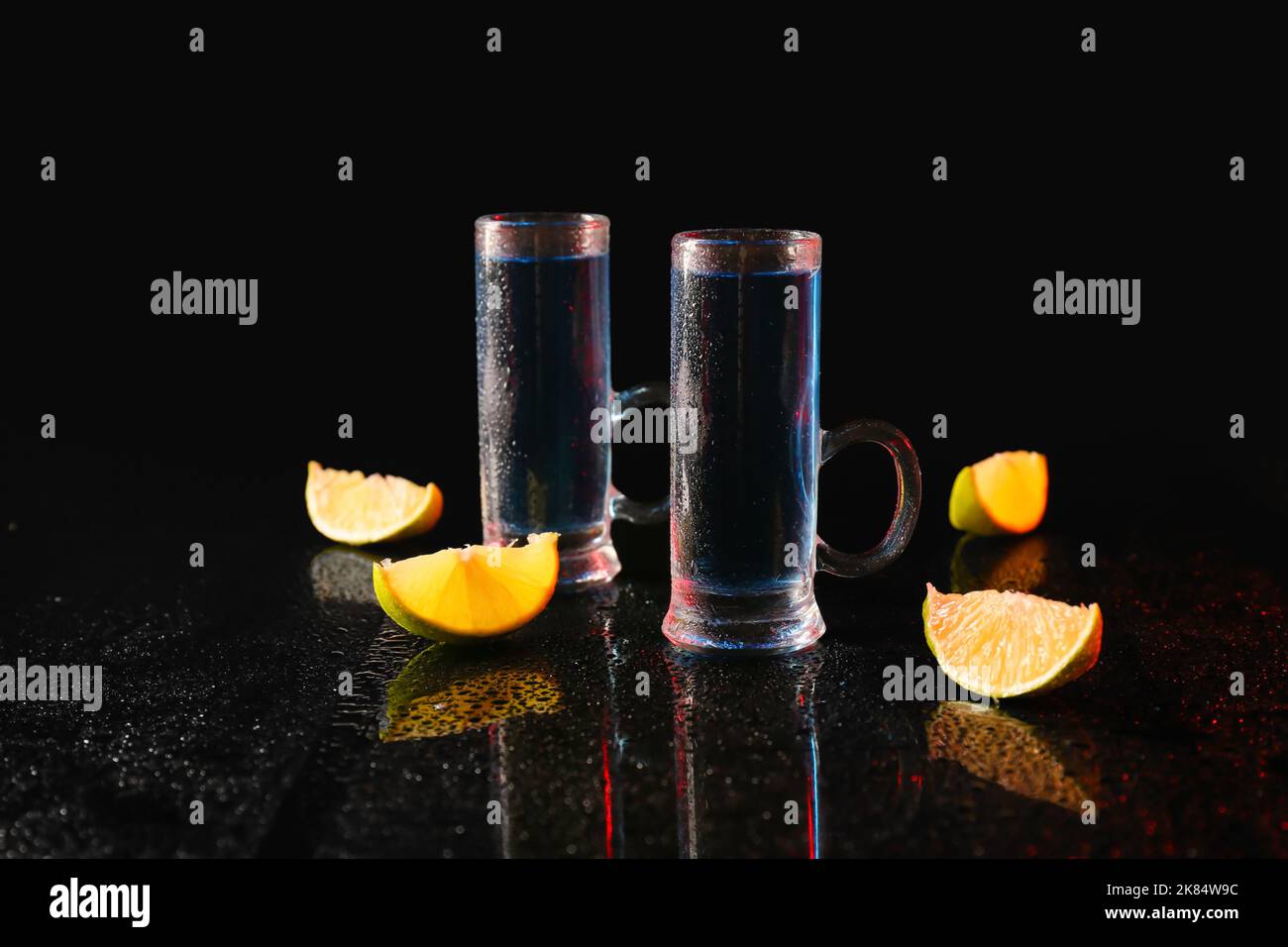 Delicious chilled shot cocktails and slices of lime on dark background ...